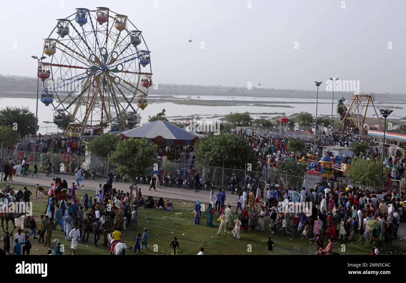 Pakistani families visit a fun fair on the bank of the Ravi River to ...