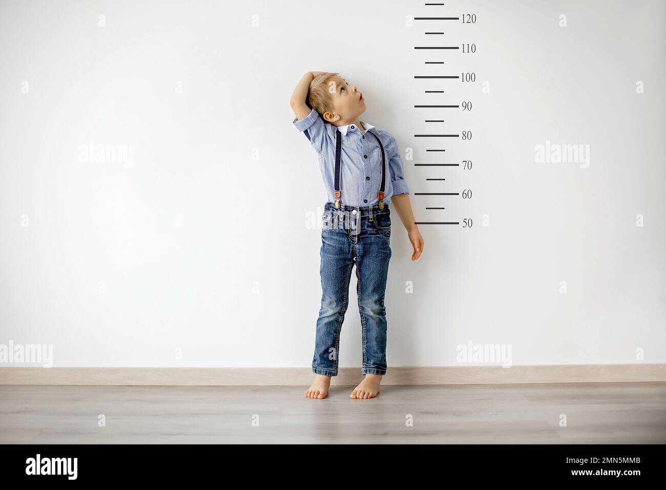 Little child, blond boy, measuring height against wall in room Stock ...