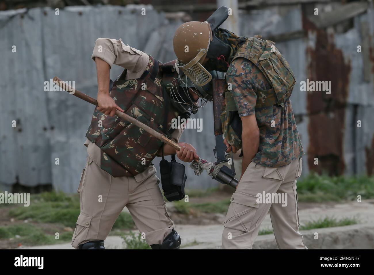 Indian police men use cloth and a bamboo stick to clean the barrel of ...