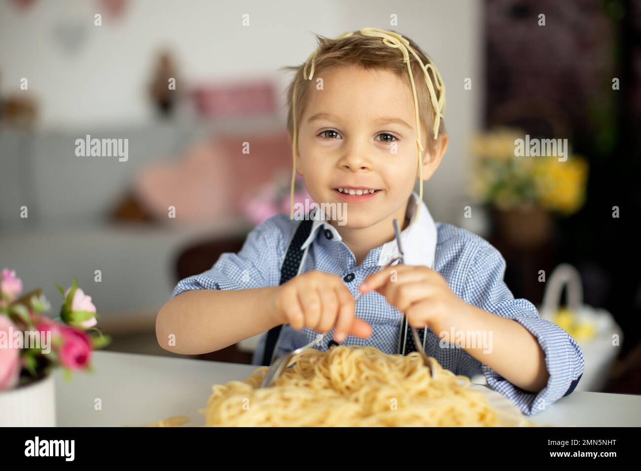 Cute preschool child, blond boy, eating spaghetti at home, making a ...