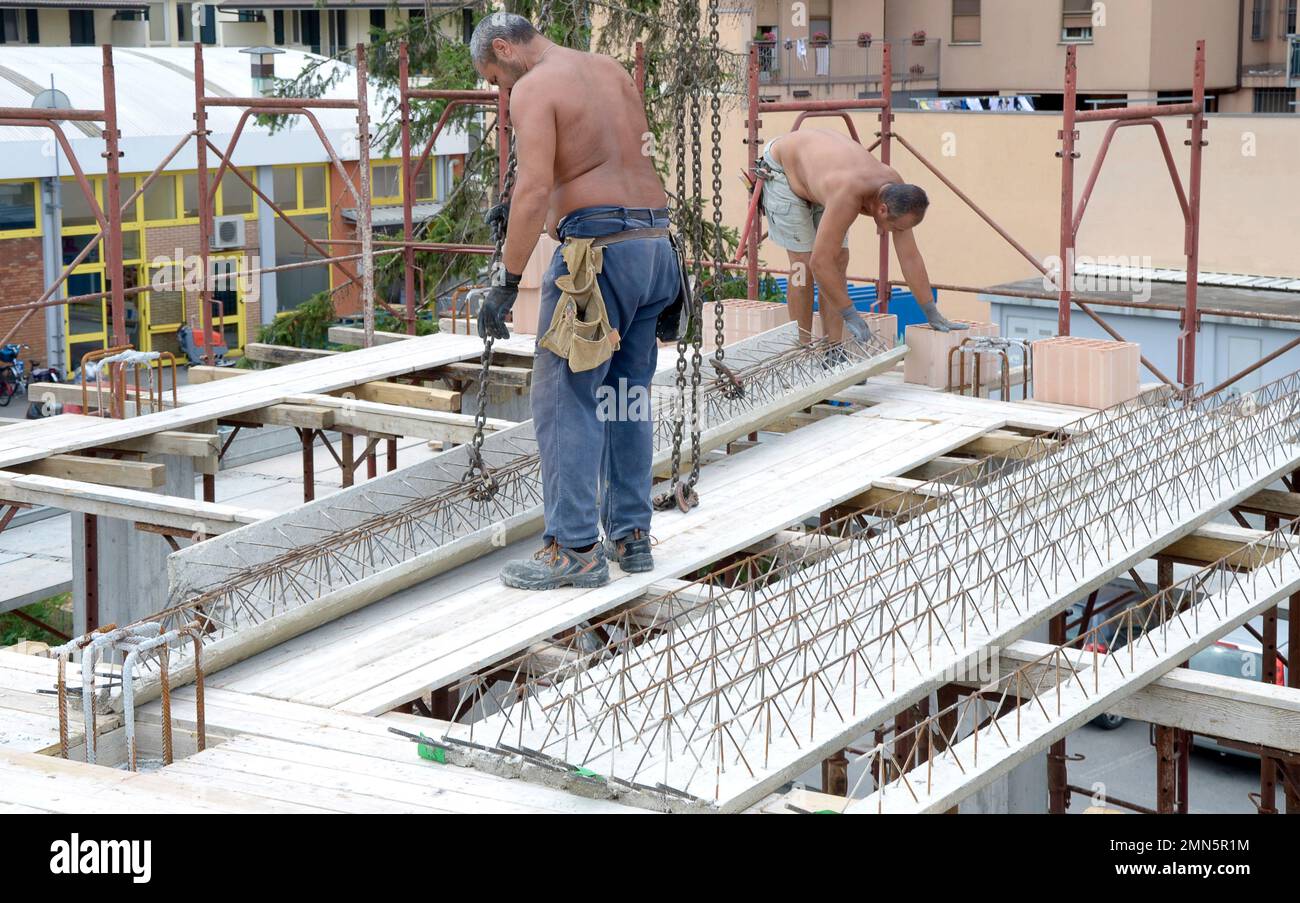 Iron workers unloading reinforcing steel from crane for construct Stock ...