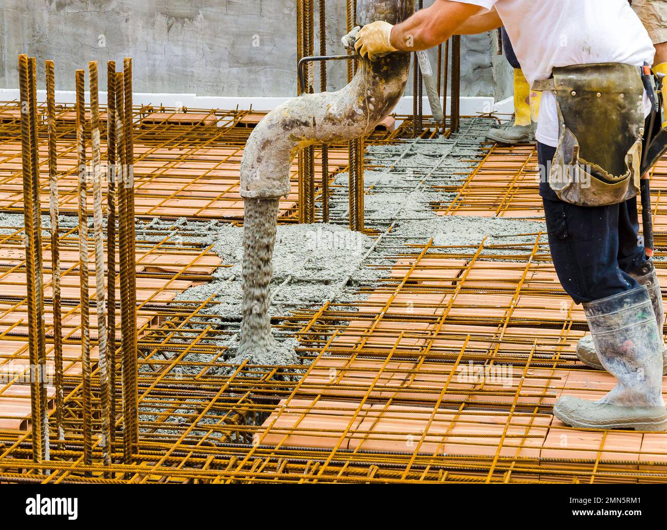 Construction worker pouring concrete into steel rebar frame Stock Photo - Alamy