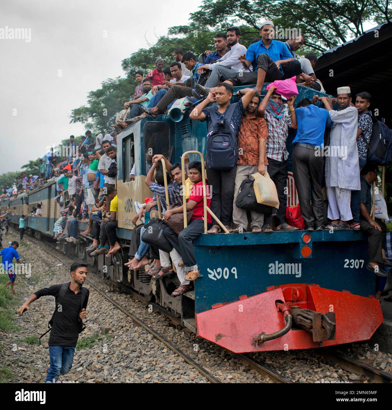 Bangladeshi Muslims hang on precariously by the engine of a train to travel home for Eid al-Fitr ...