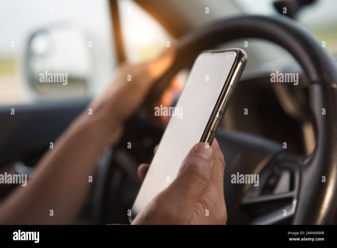 The driver's hand behind the wheel holds a smartphone. Navigator ...