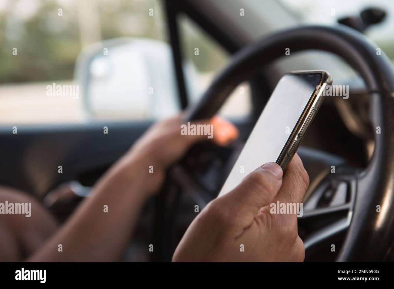 The driver's hand behind the wheel holds a smartphone. Navigator ...