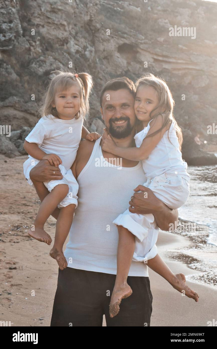 Daddy's love and care. The father holds two daughters in his arms ...