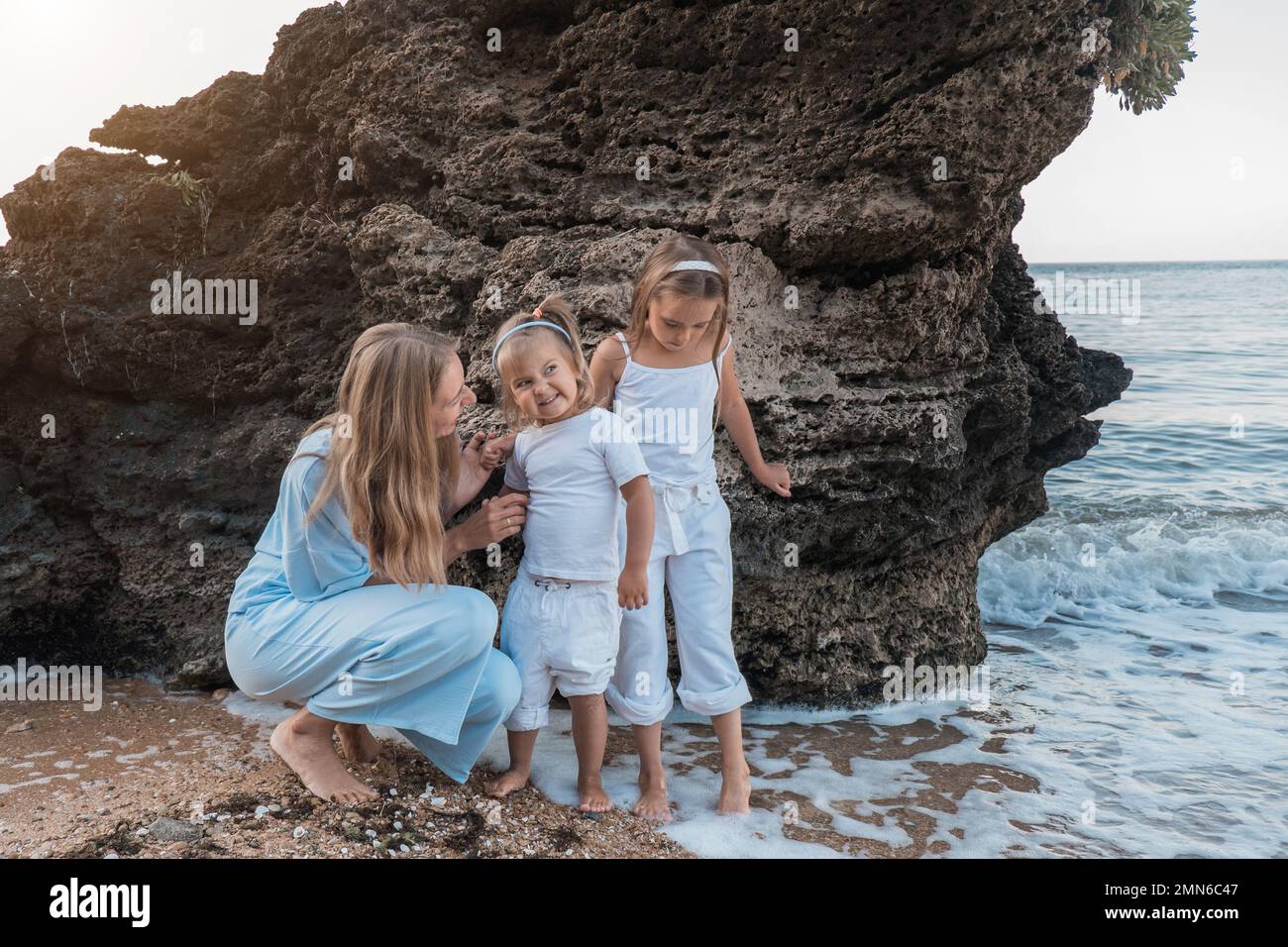 Mother's love. Mom hugs her daughters, kisses and plays, tenderness and ...