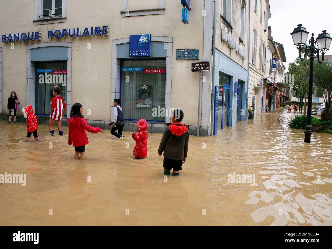 Children walk on a flooded street caused by heavy rain and thunder ...