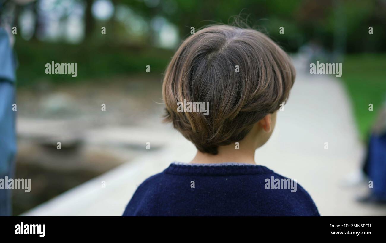 Back of child walking at park. One small boy head looking around ...