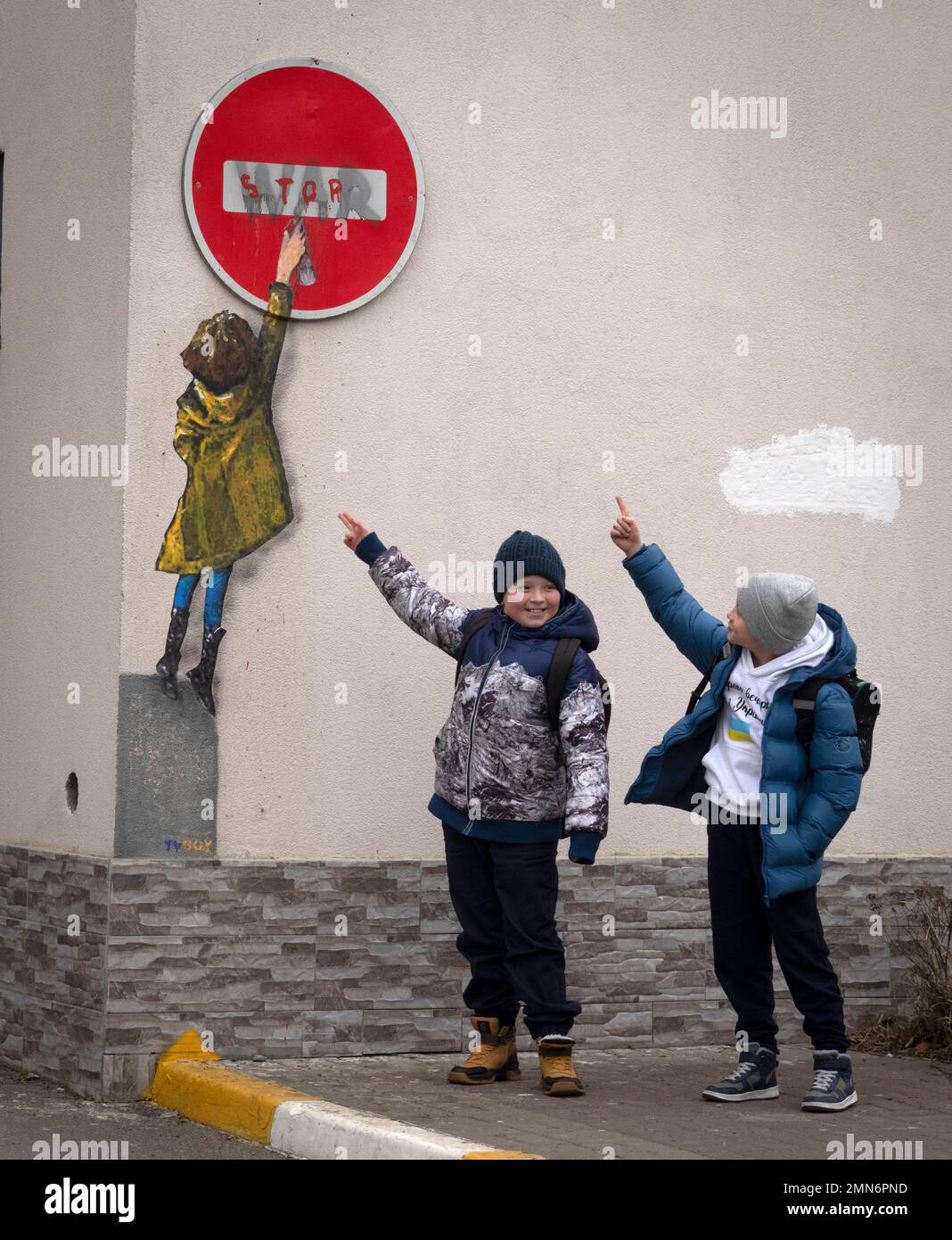 Boys point at an artwork by famous street artist TvBoy in the town ...