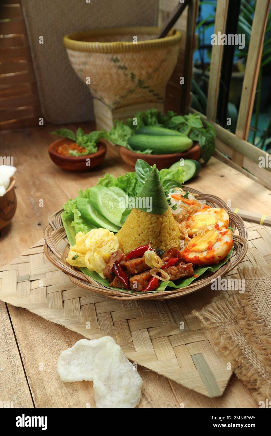 Indonesian traditional serving of Nasi Tumpeng on a rustic table Stock ...