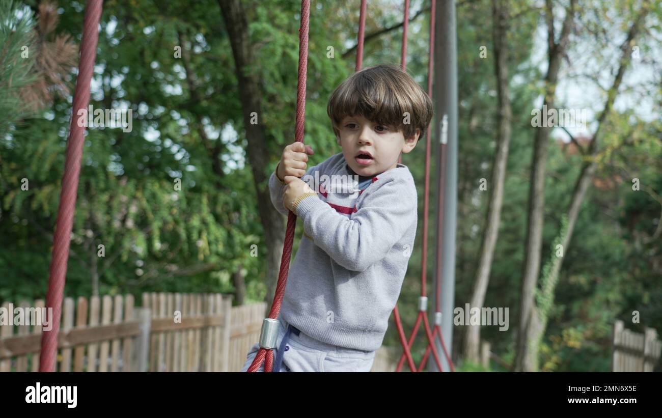 Playful little boy keeping balance at playground structure. Child ...