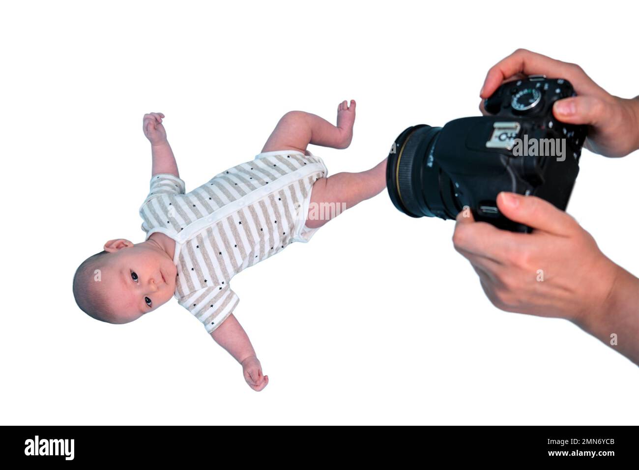 A photographer takes pictures of a newborn baby with a camera in studio ...