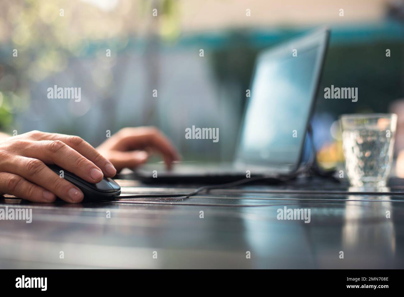 Working at a laptop in the outdoor courtyard - men's hands close-up ...