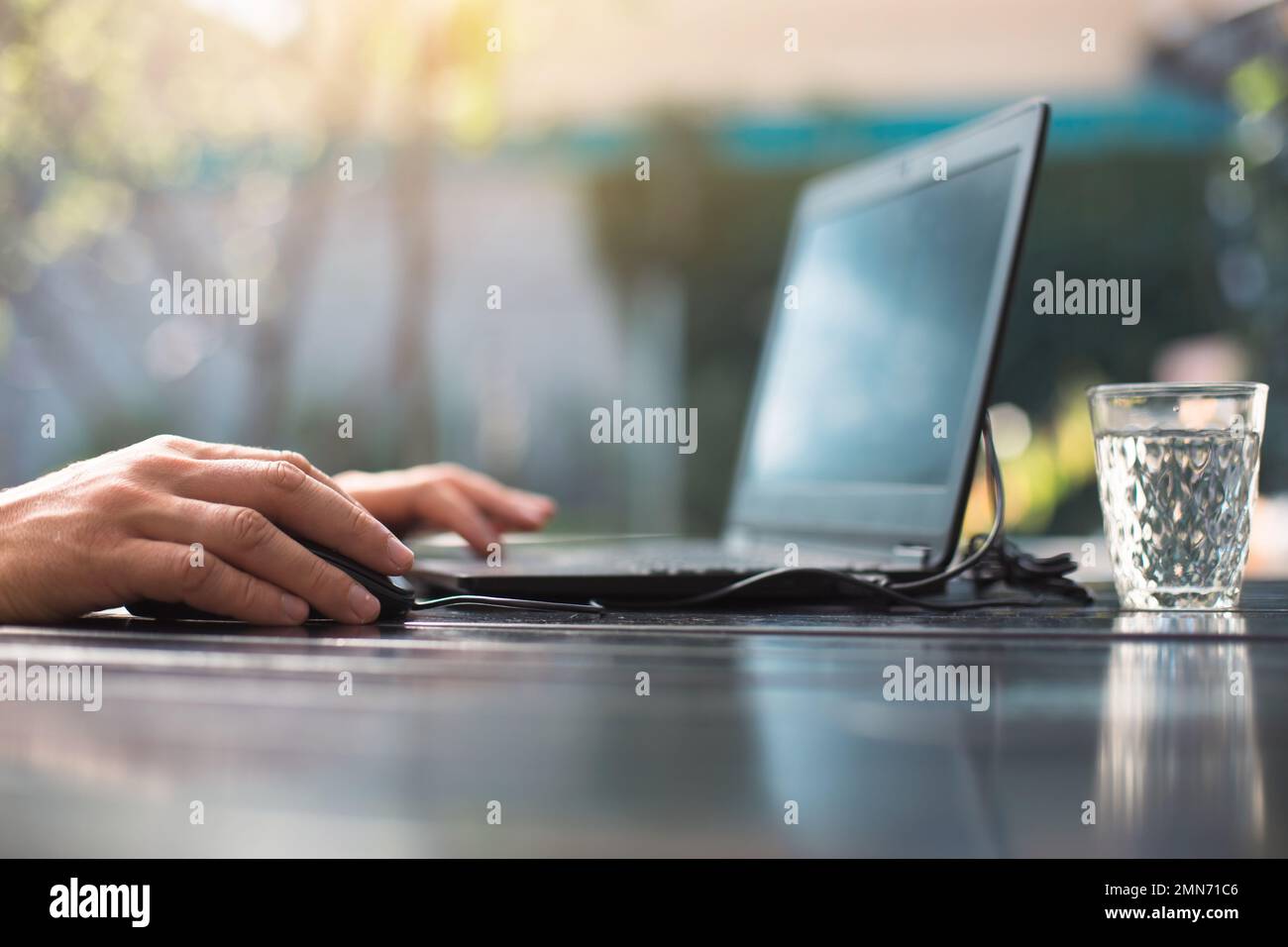 Working at a laptop in the outdoor courtyard - men's hands close-up ...