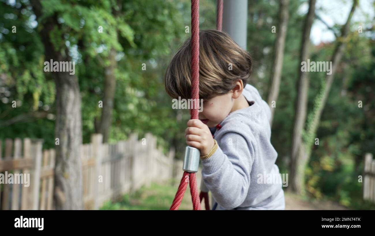 Little boy reaching for rope at playground structure. Active child ...