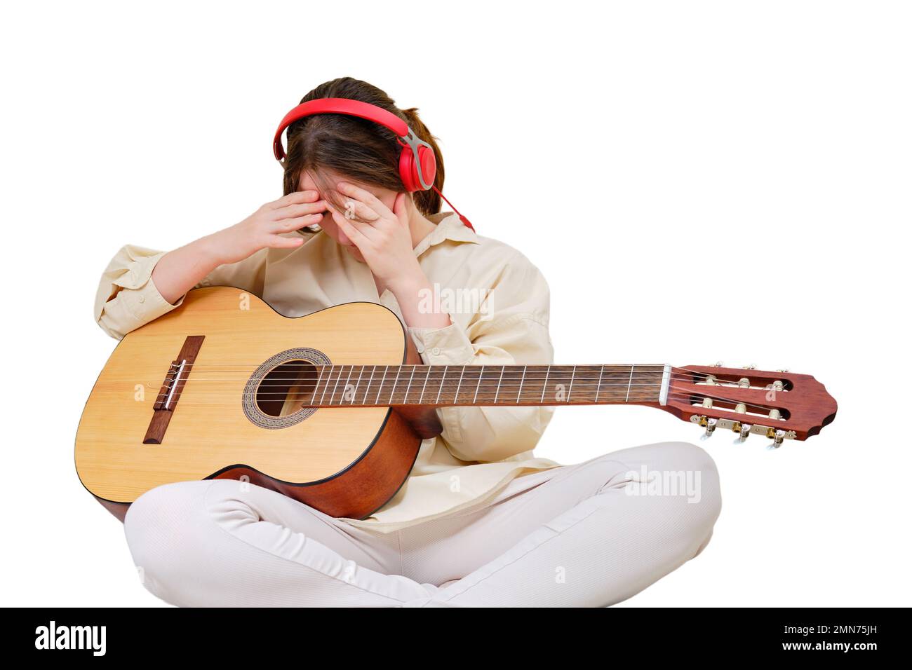 A shamed crying woman with acoustic guitar sitting on a bed in a home ...
