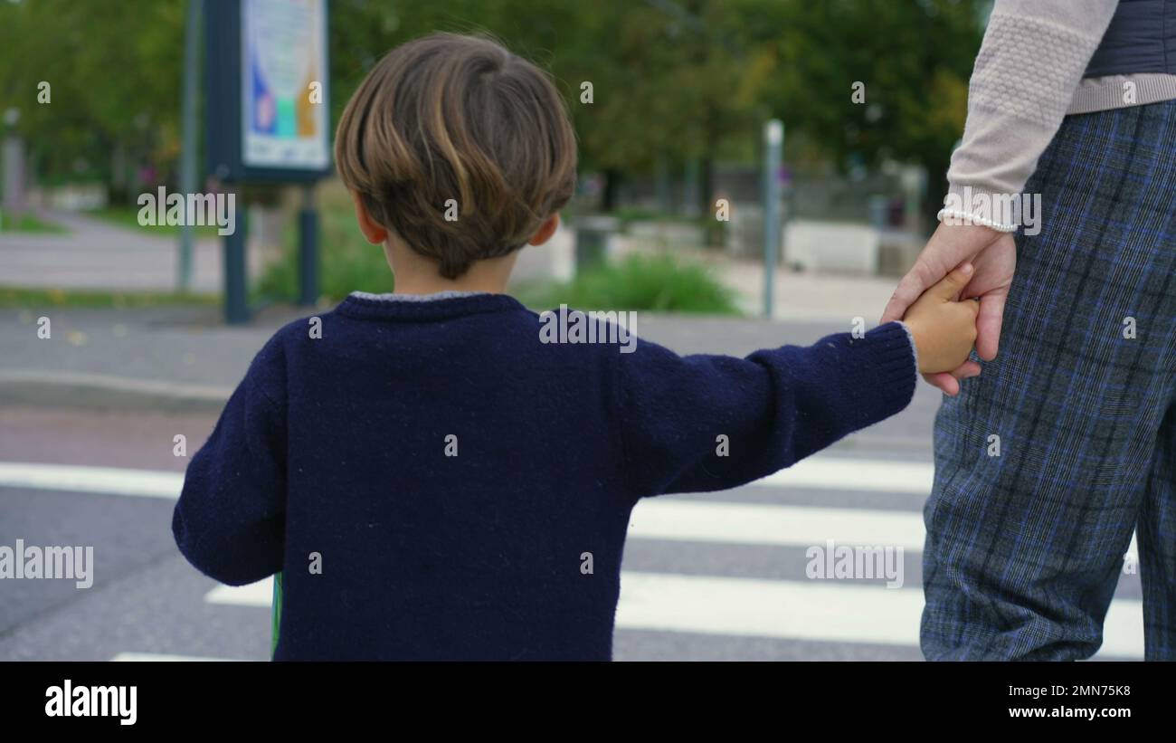 Mother crossing street with child. Little boy holding hand at crosswalk ...