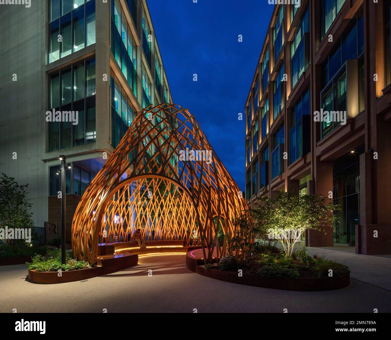 Wooden pavilion illuminated and glowing up in between a row of office ...
