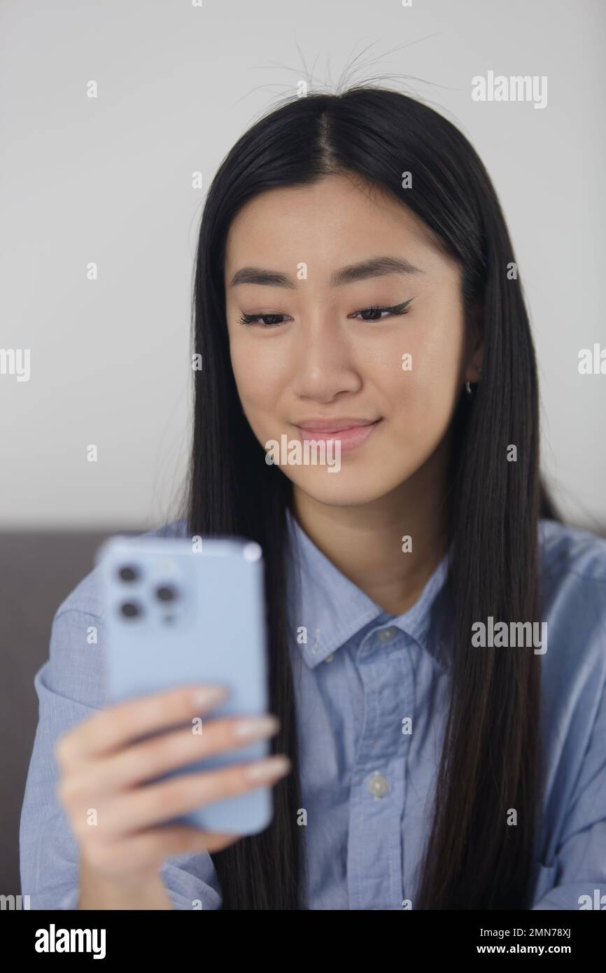 Portrait of beautiful asian girl browsing mobile app on smart phone ...