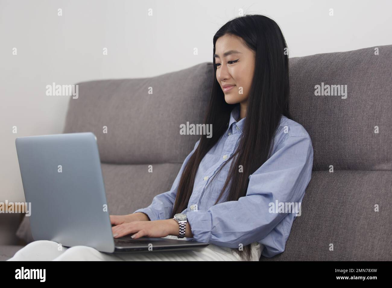 Vietnamese POC girl typing code on computer. Cheerful BIPOC female coding on modern laptop at ...