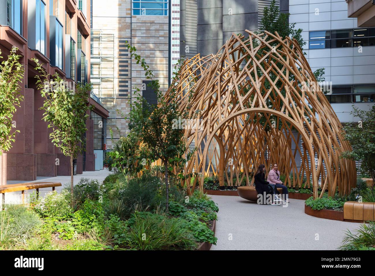 Two people sitting on the rotating bench inside one of the pavilions ...