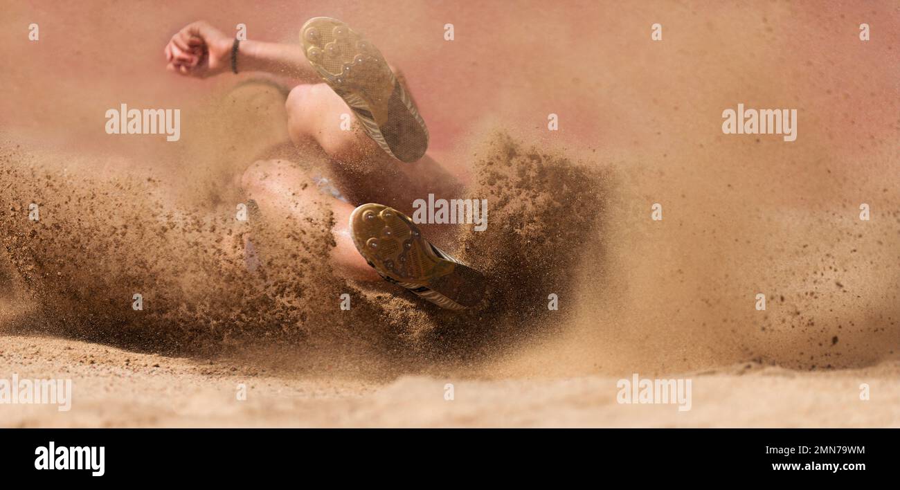 Female athlete long jump landing sand spray Stock Photo - Alamy