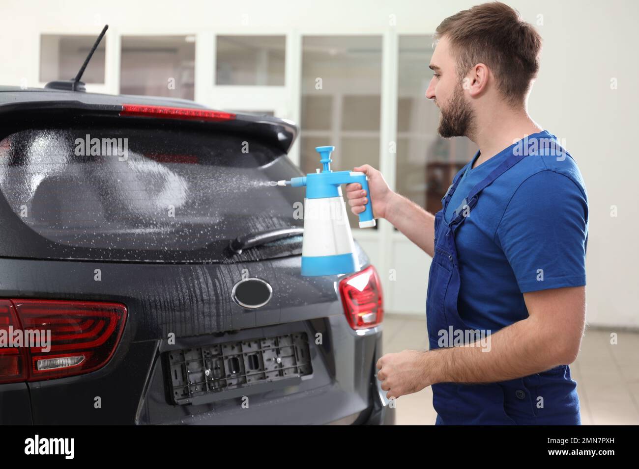 Worker spraying water onto car window before tinting Stock Photo - Alamy
