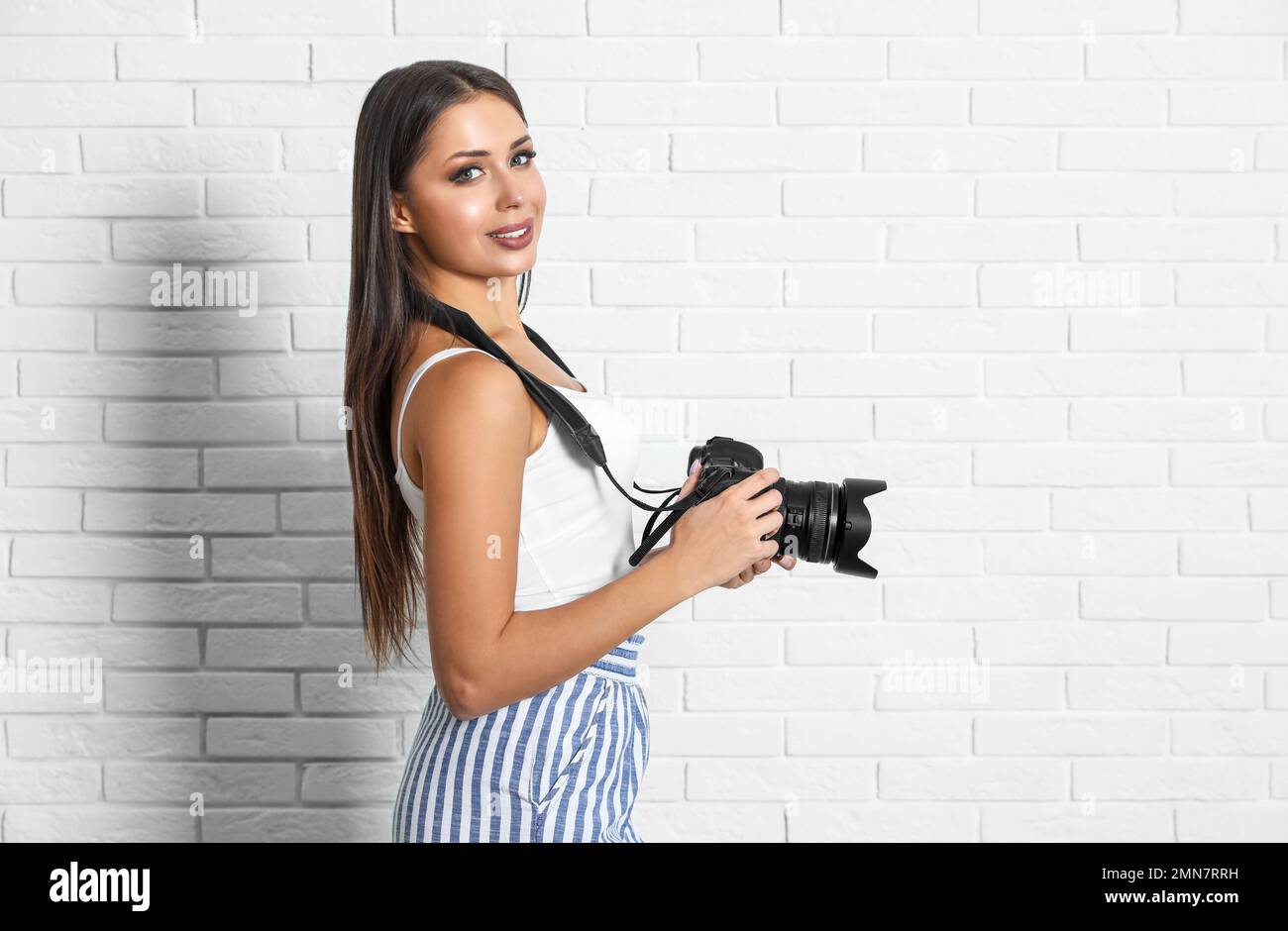 Professional photographer working near white brick wall in studio Stock ...