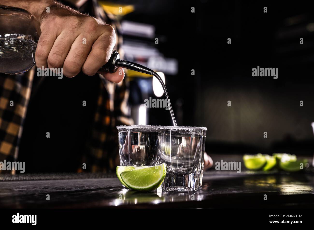 Bartender pouring Mexican Tequila into shot glasses at bar counter, closeup Stock Photo - Alamy