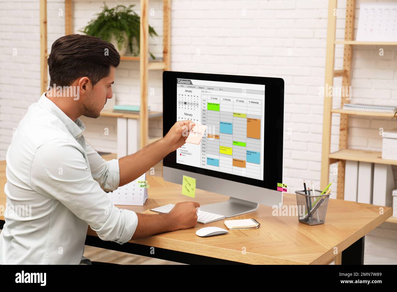 Handsome man using calendar app on computer in office Stock Photo - Alamy