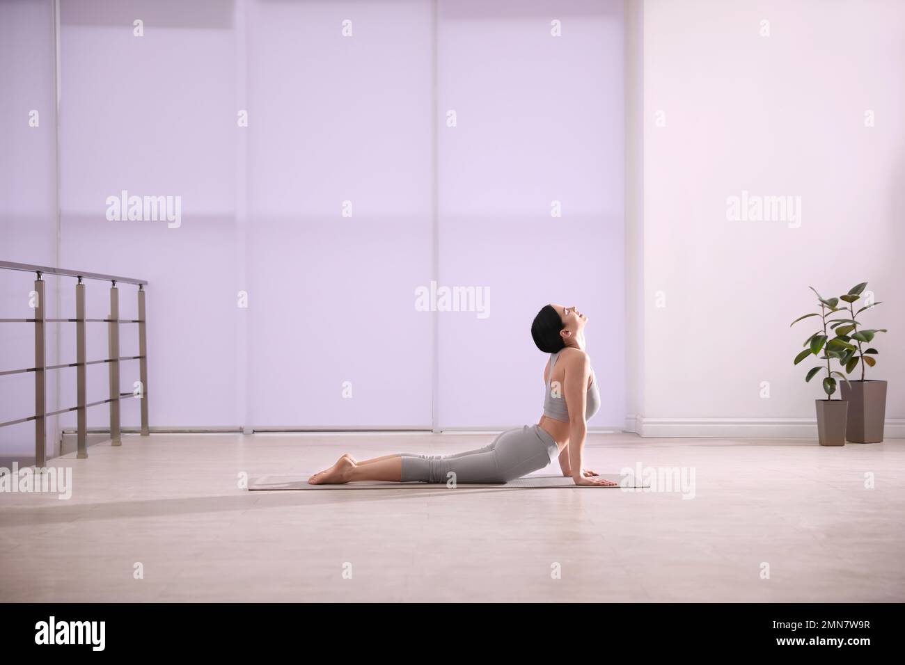 Young woman practicing cobra asana in yoga studio. Bhujangasana pose ...