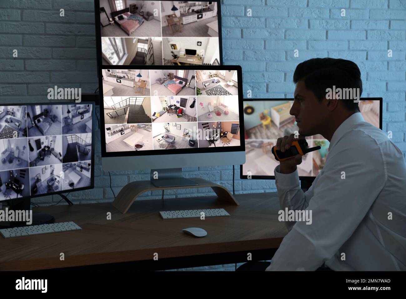 Male security guard with portable transmitter monitoring cameras at ...