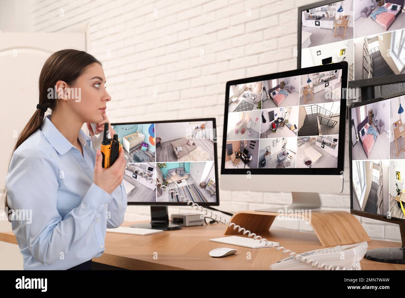 Female security guard talking by telephone near monitors at workplace ...