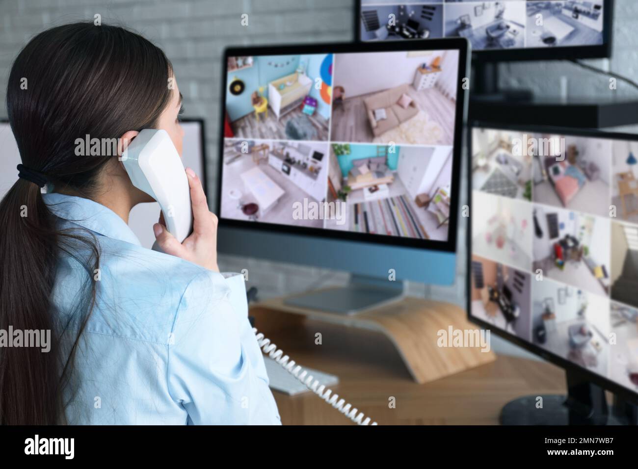 Female security guard talking by telephone near monitors at workplace ...