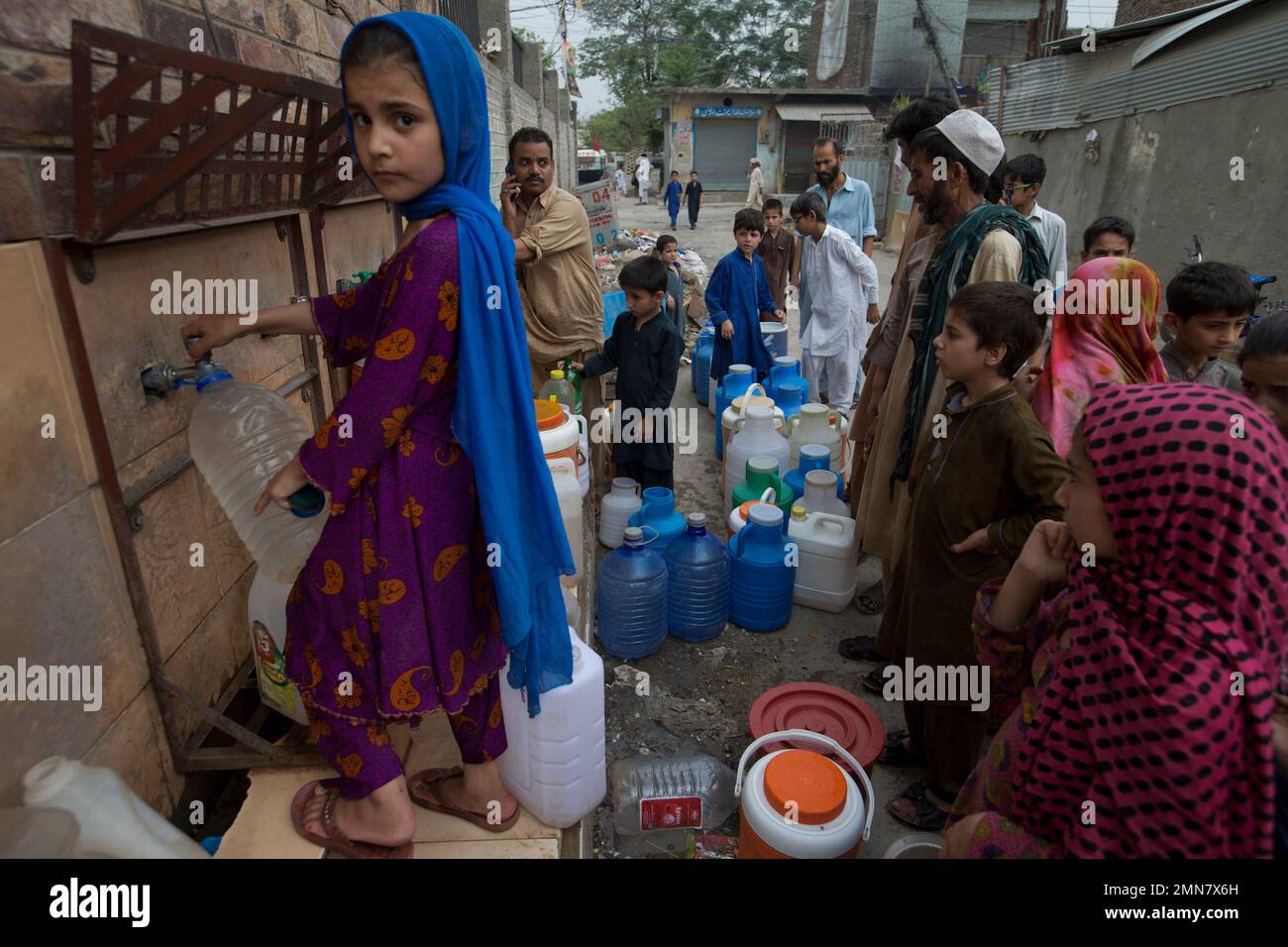 People wait for their turn to fill containers with clean water in ...
