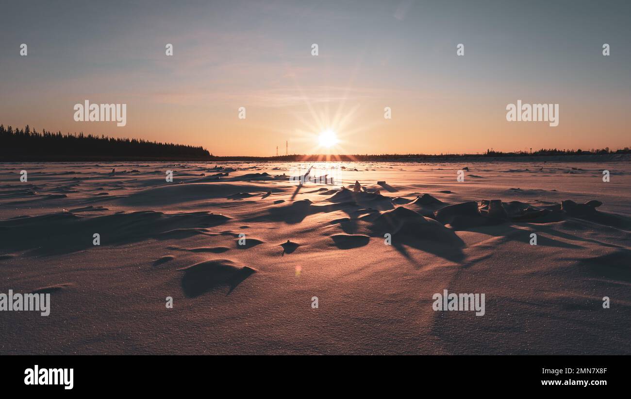 The bright sun at sunset sets on the Vilyui River in Yakutia in winter ...