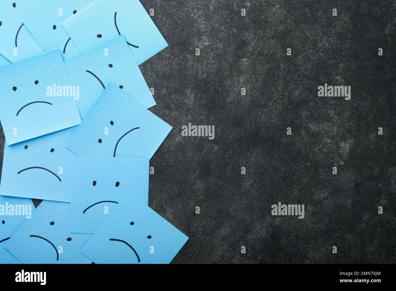 Blue sticky notes blank with drawing sad face on black background with ...