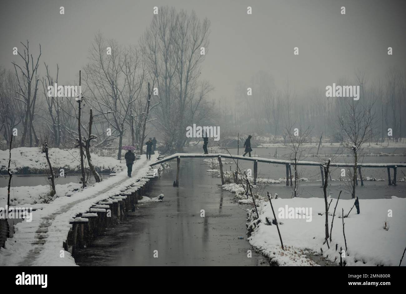 Srinagar, India. 30th Jan, 2023. People walk on snow covered wooden ...