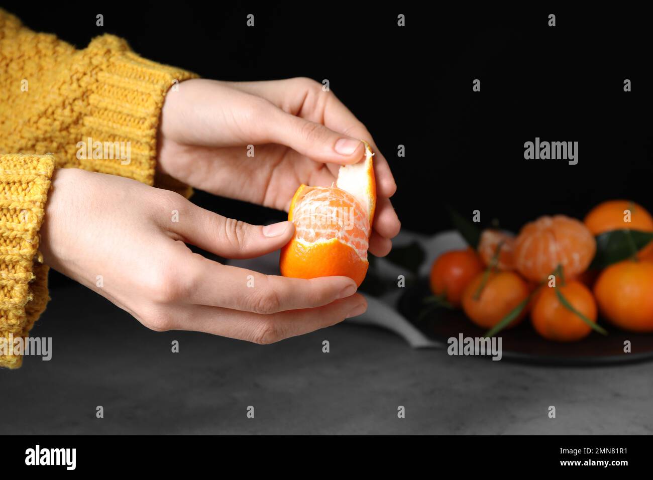 Woman peeling fresh ripe tangerine on black background, closeup Stock ...