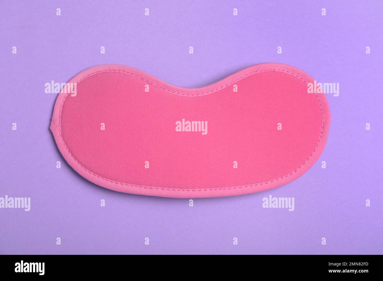 Pink sleeping mask on violet background, top view. Bedtime accessory ...
