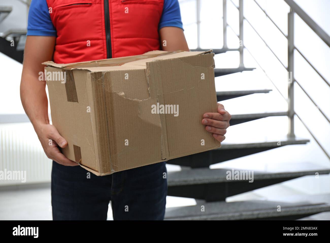 Courier with damaged cardboard box indoors, closeup. Poor quality ...