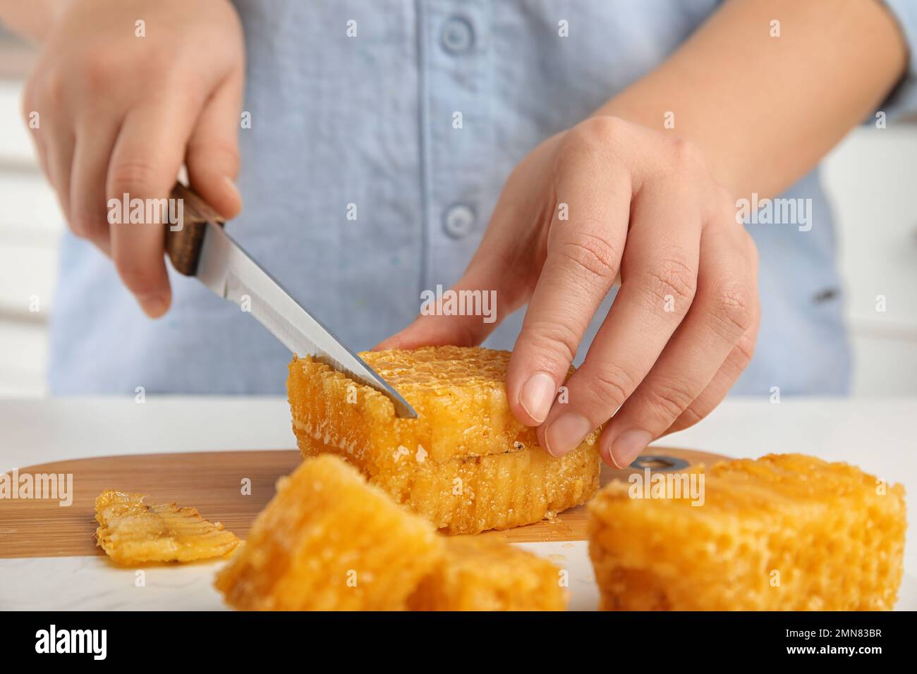 Woman cutting fresh honeycomb at table, closeup Stock Photo - Alamy