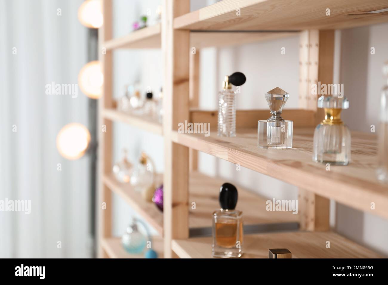 Different perfume bottles on wooden rack indoors Stock Photo - Alamy