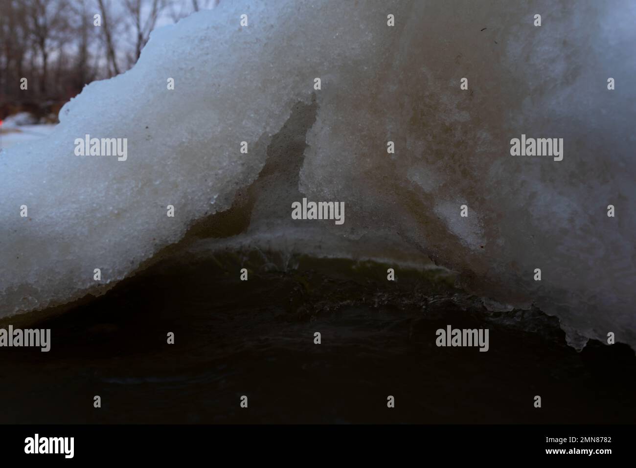 The first ice with snow on the river bank rises in waves from the wind ...