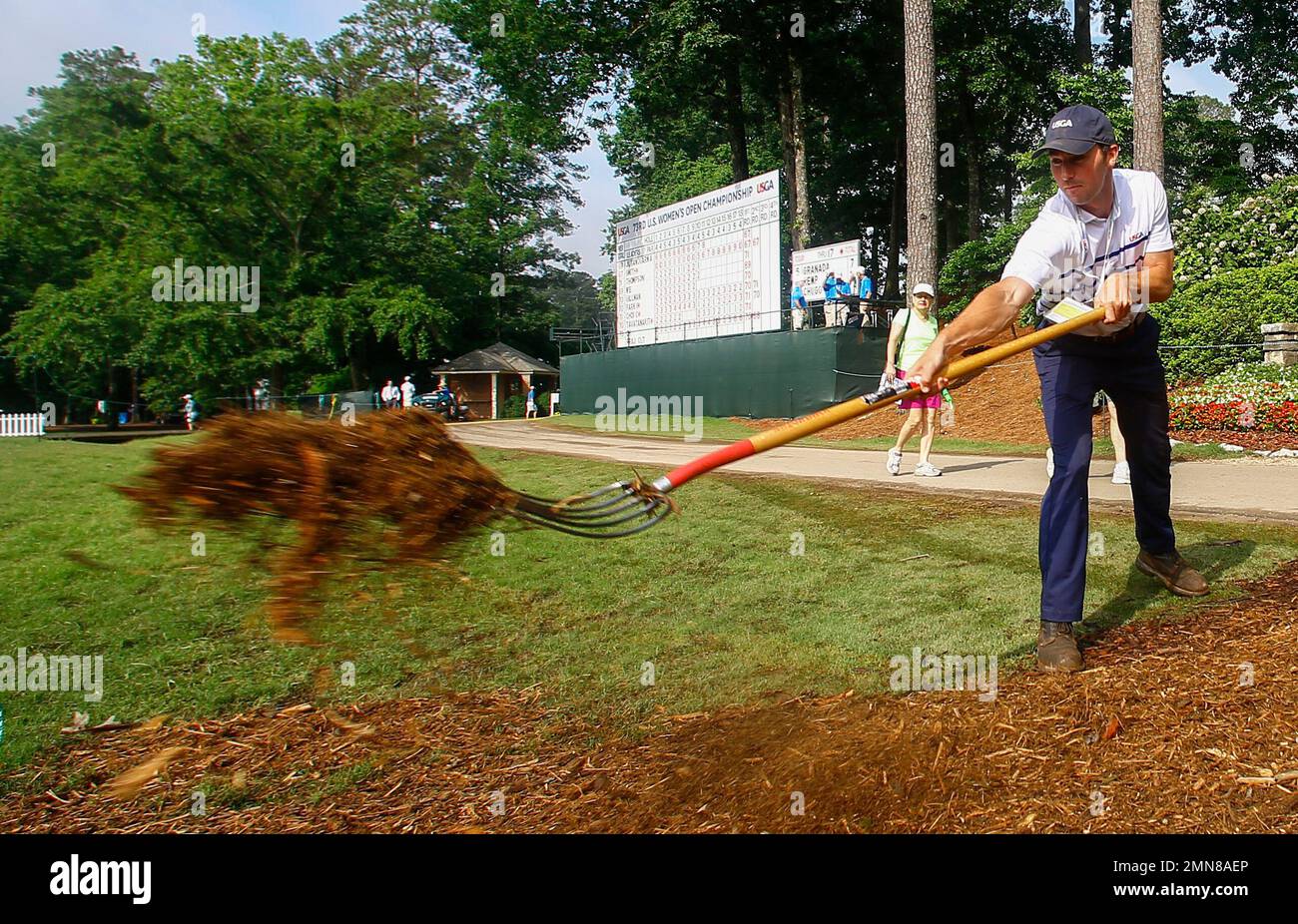 Joh Willard with the USGA spreads mulch on a muddy path during the ...