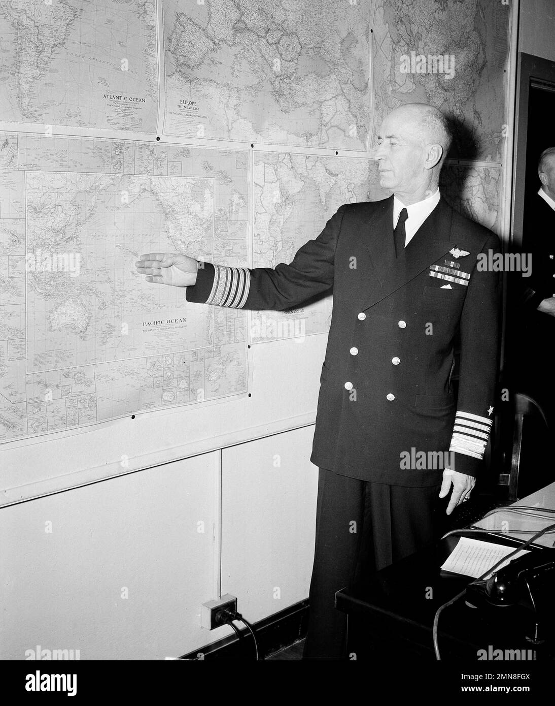 Adm. Ernest J. King, commander-in-chief of the U.S. Fleet, pointing to Hawaii on a large map of ...
