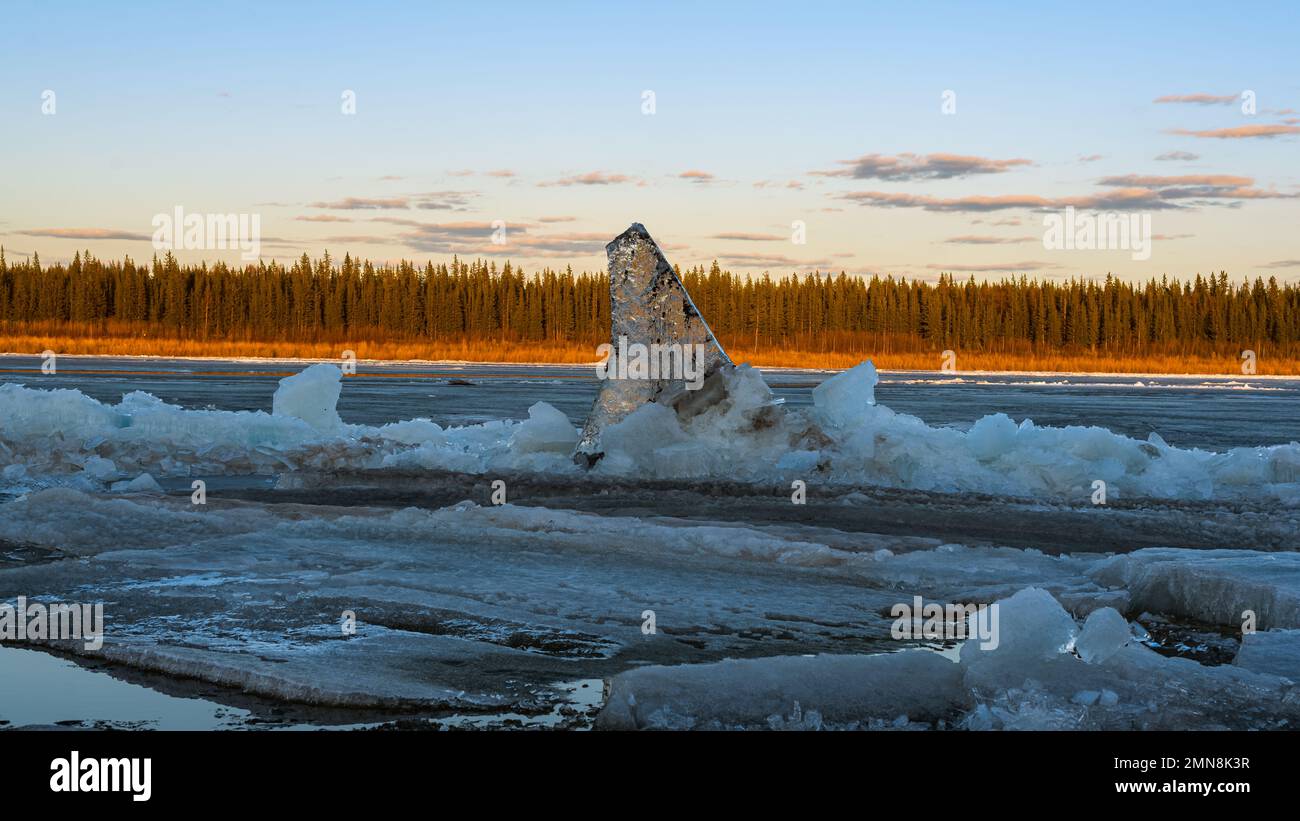 An ice floe in the form of a shark's fin with the reflection of clouds ...