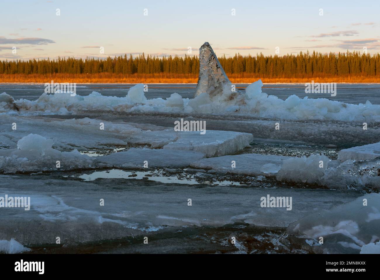 An ice floe in the form of a shark's fin with the reflection of clouds ...