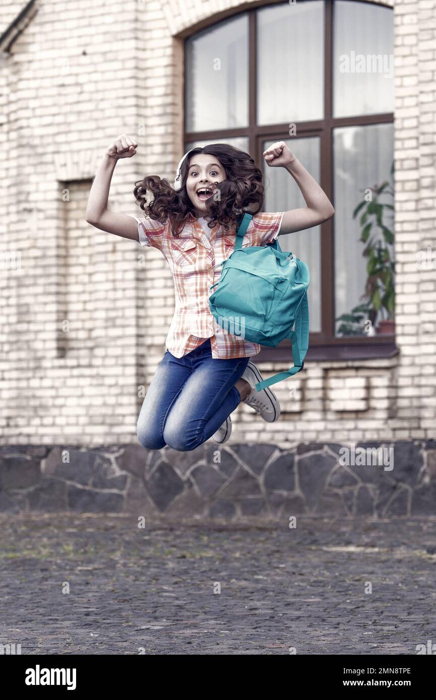 Happy energetic kid jump with school bag in casual style in schoolyard ...